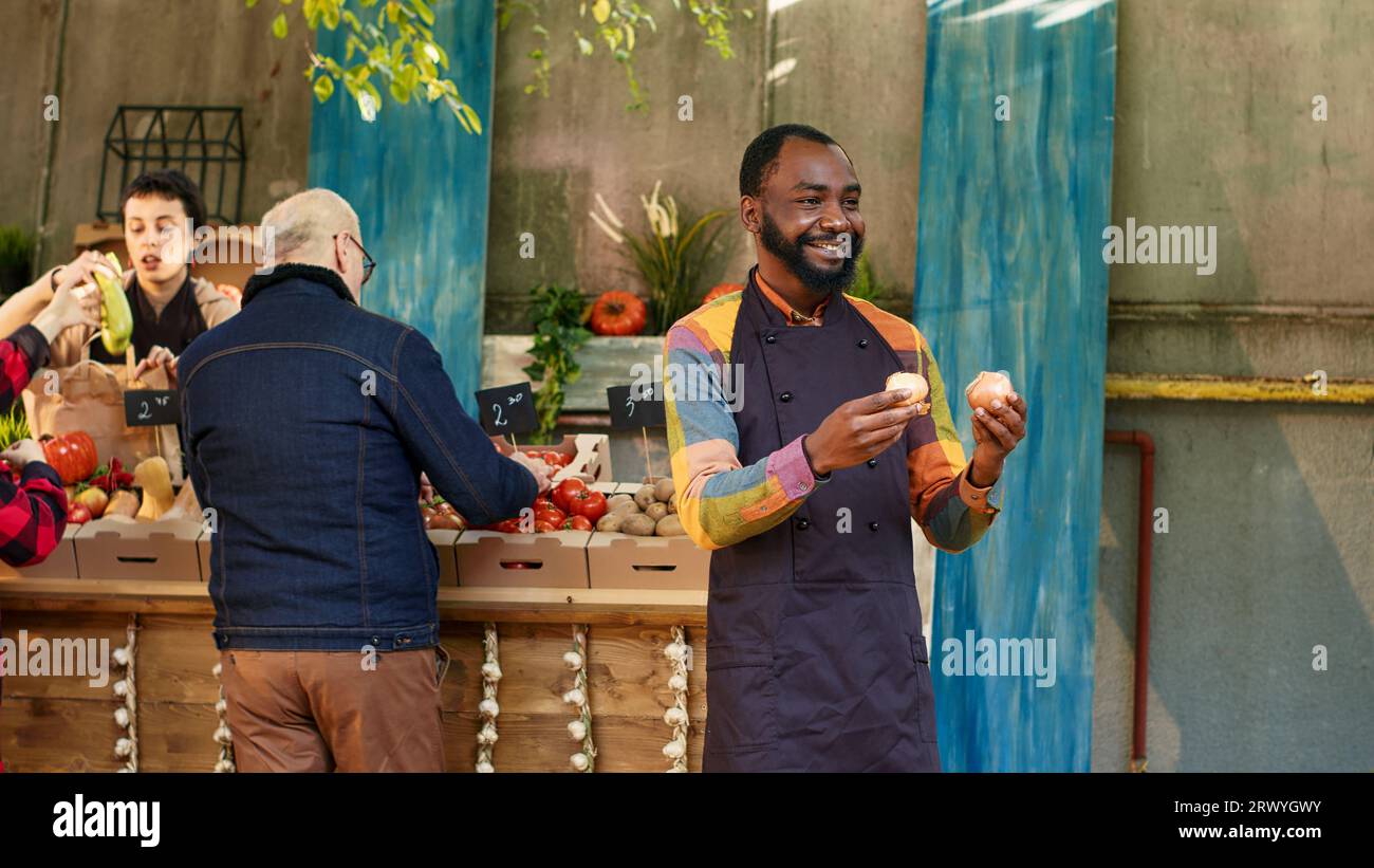 African american vendor with apron holding colorful eco produce to show ...