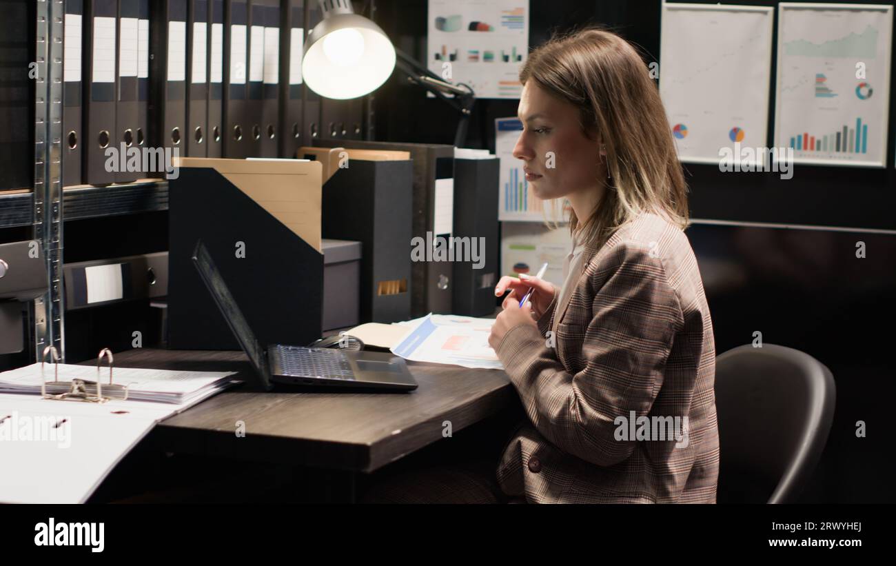 Focused caucasian female law officer accurately examining evidence with ...