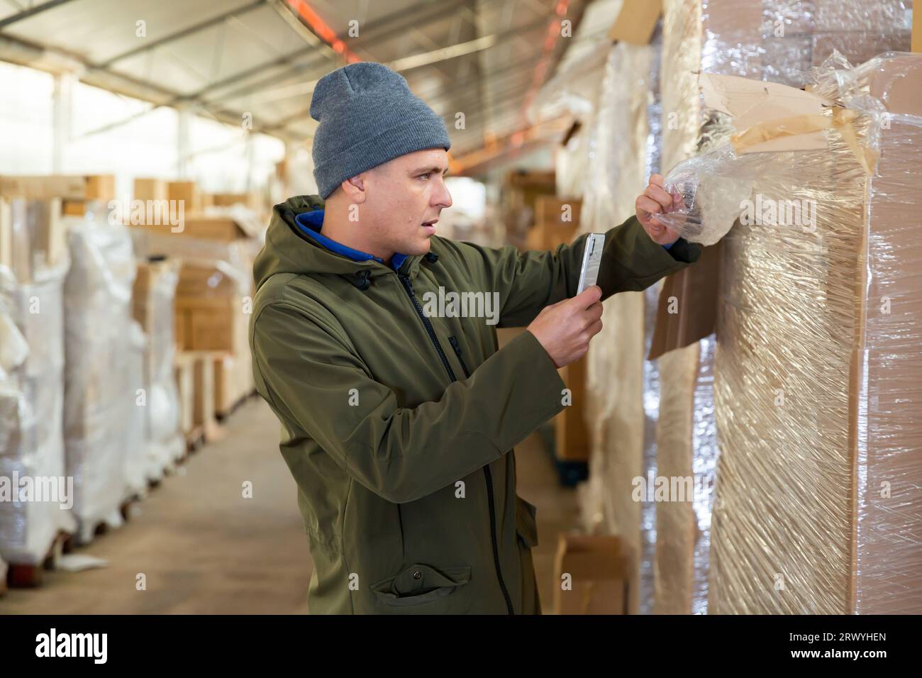 Store worker scans qr code on boxes using smartphone in warehouse shop ...