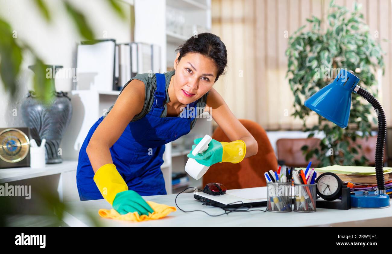 Asian female cleaning desk in office Stock Photo - Alamy