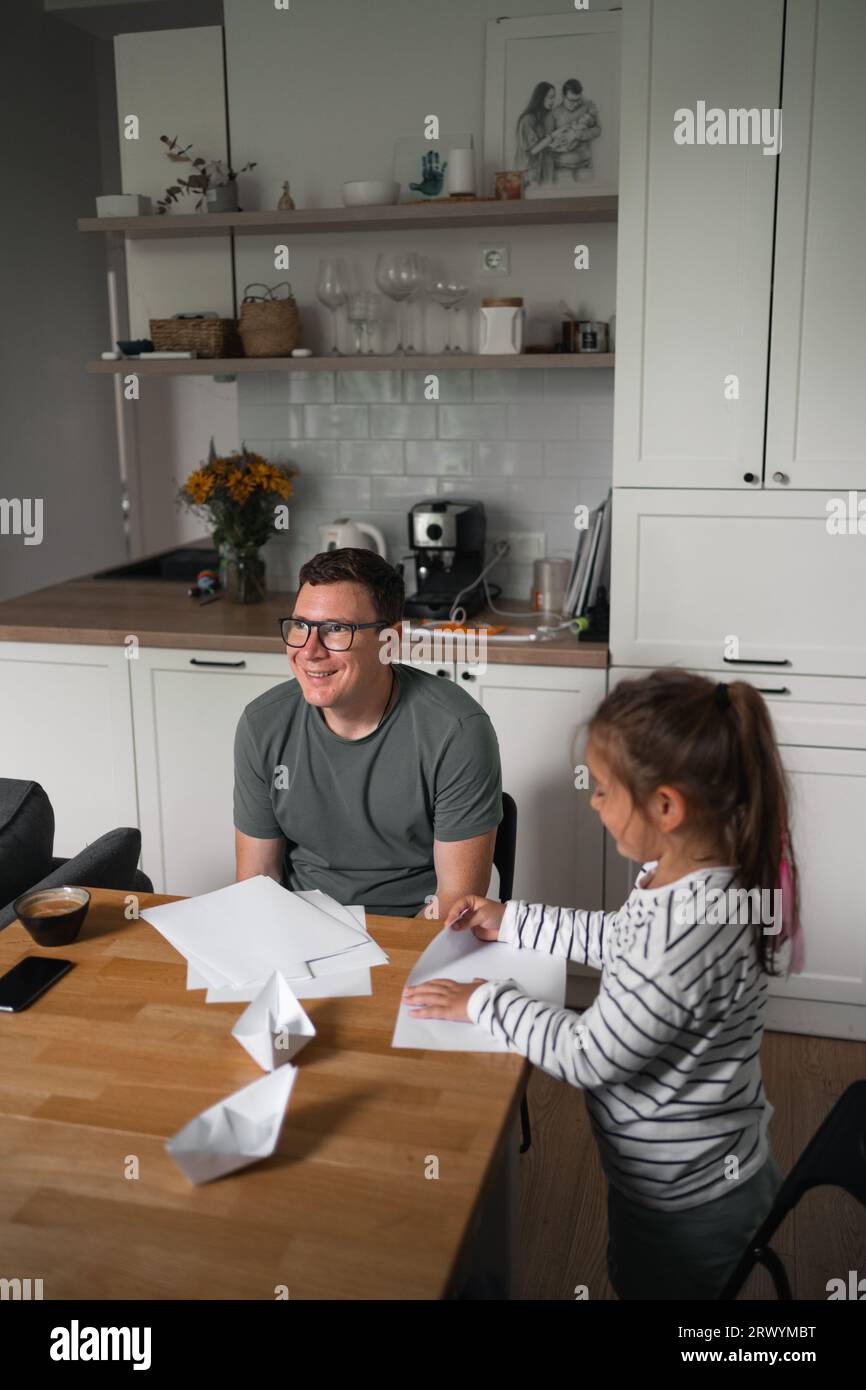 Father and child girl doing origami crafts together. Modern parenthood ...
