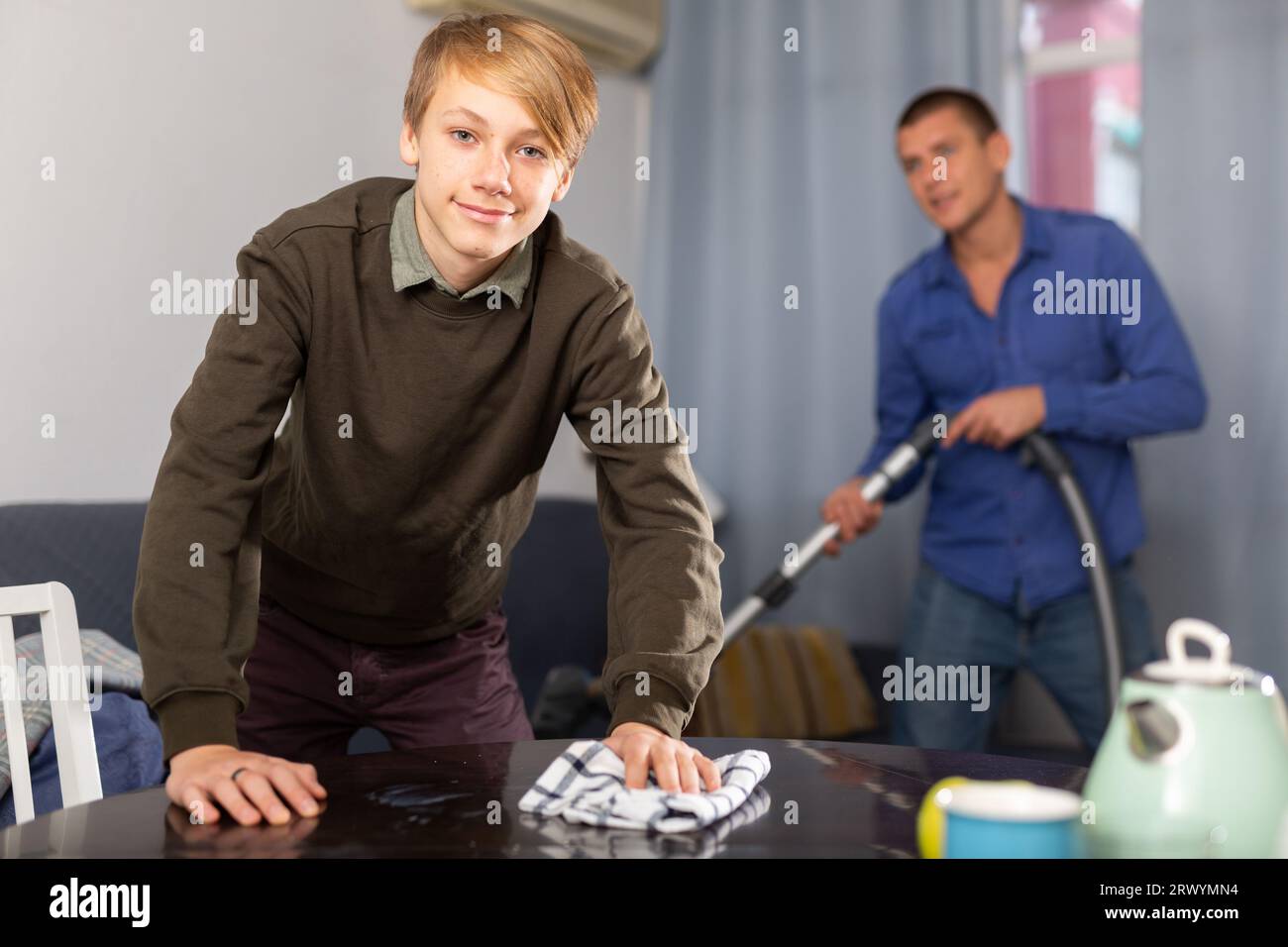 Teenager boy wiping dust from table Stock Photo - Alamy