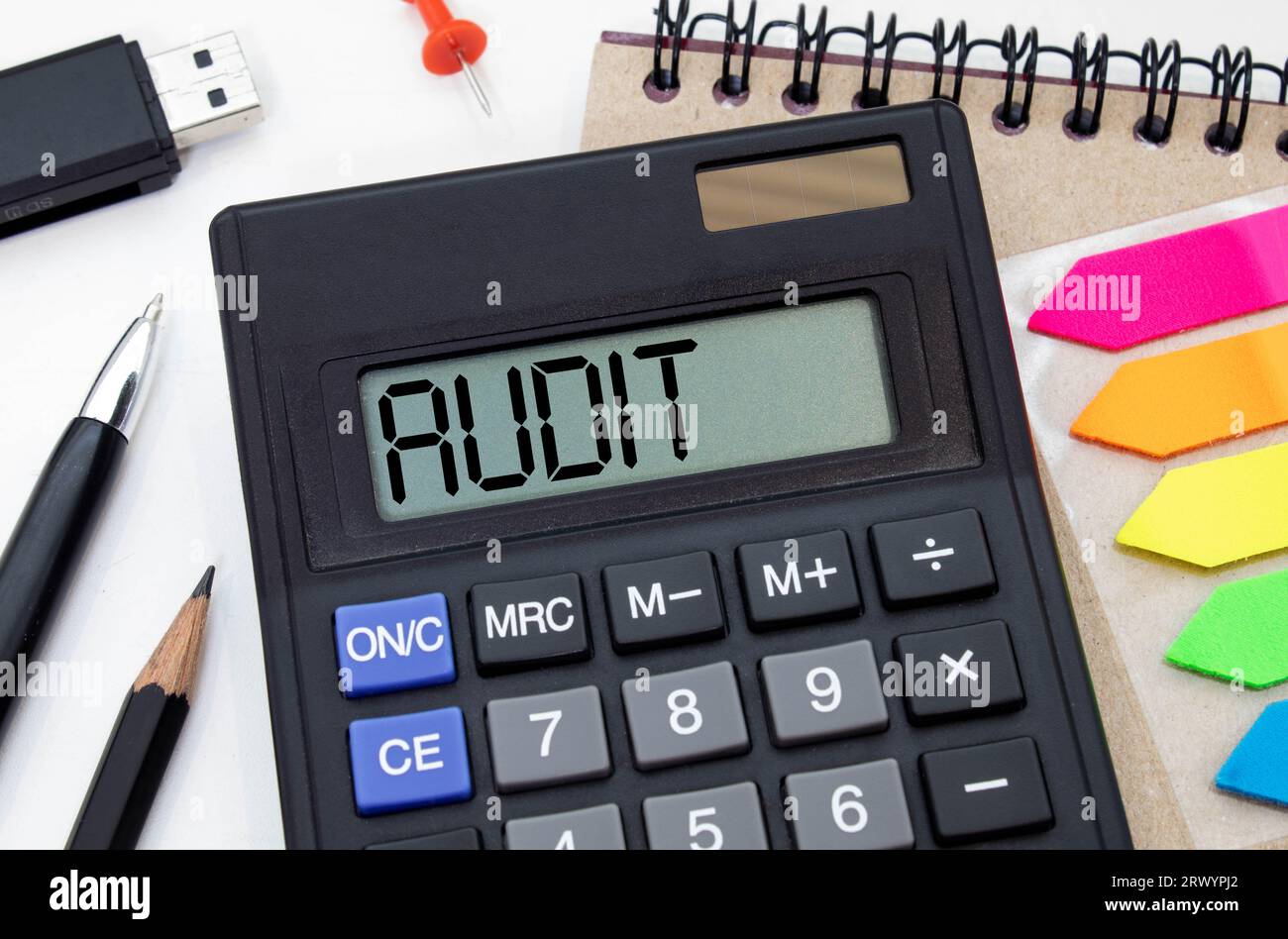 The word AUDIT is written on a sticker that lies on a calculator and ...