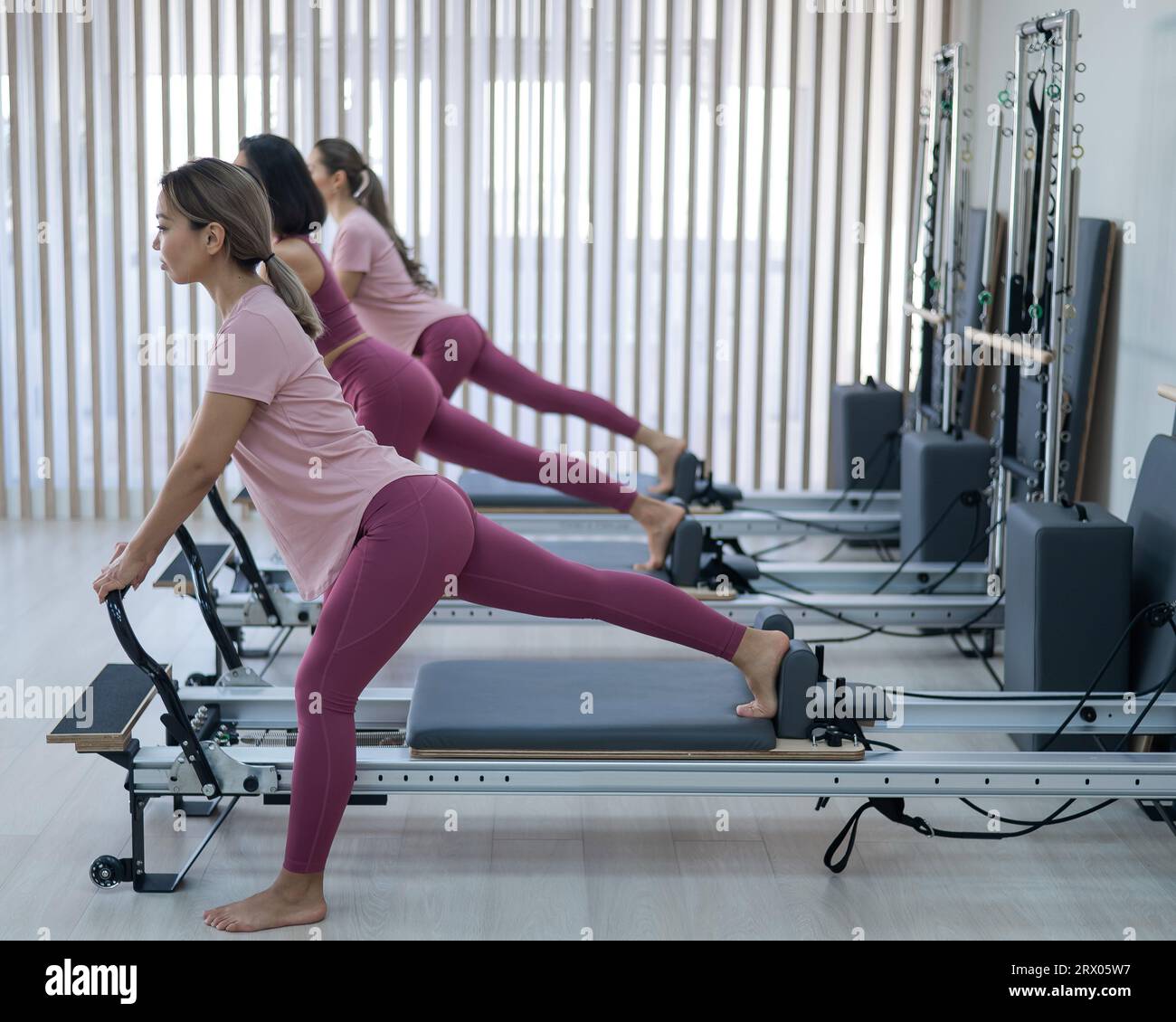 Three Asian women doing lunges on a reformer machine Stock Photo - Alamy