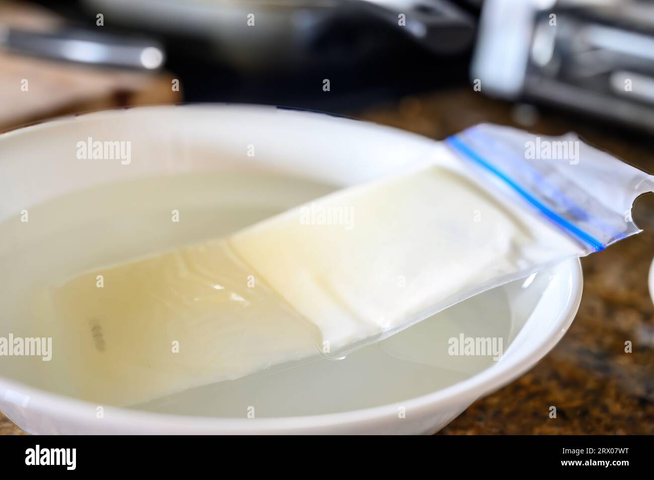 thawing frozen breast milk in bowl of warm water Stock Photo - Alamy