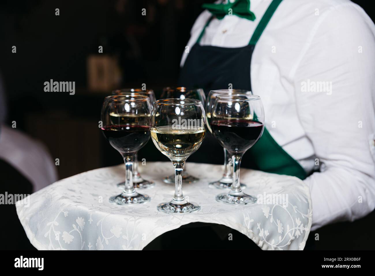 Waiter serves few glasses of red and white wine. Waiter dressed in a ...