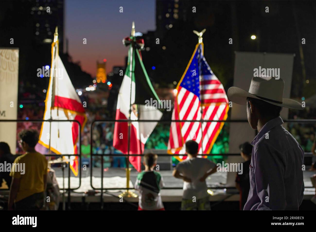 A man pauses to look at the stage and 3 flags at dusk in front of the ...