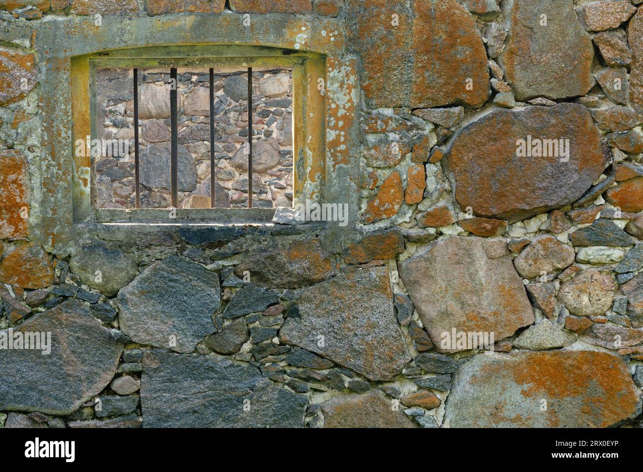 A barred window in a stone wall with a brick border Stock Photo - Alamy