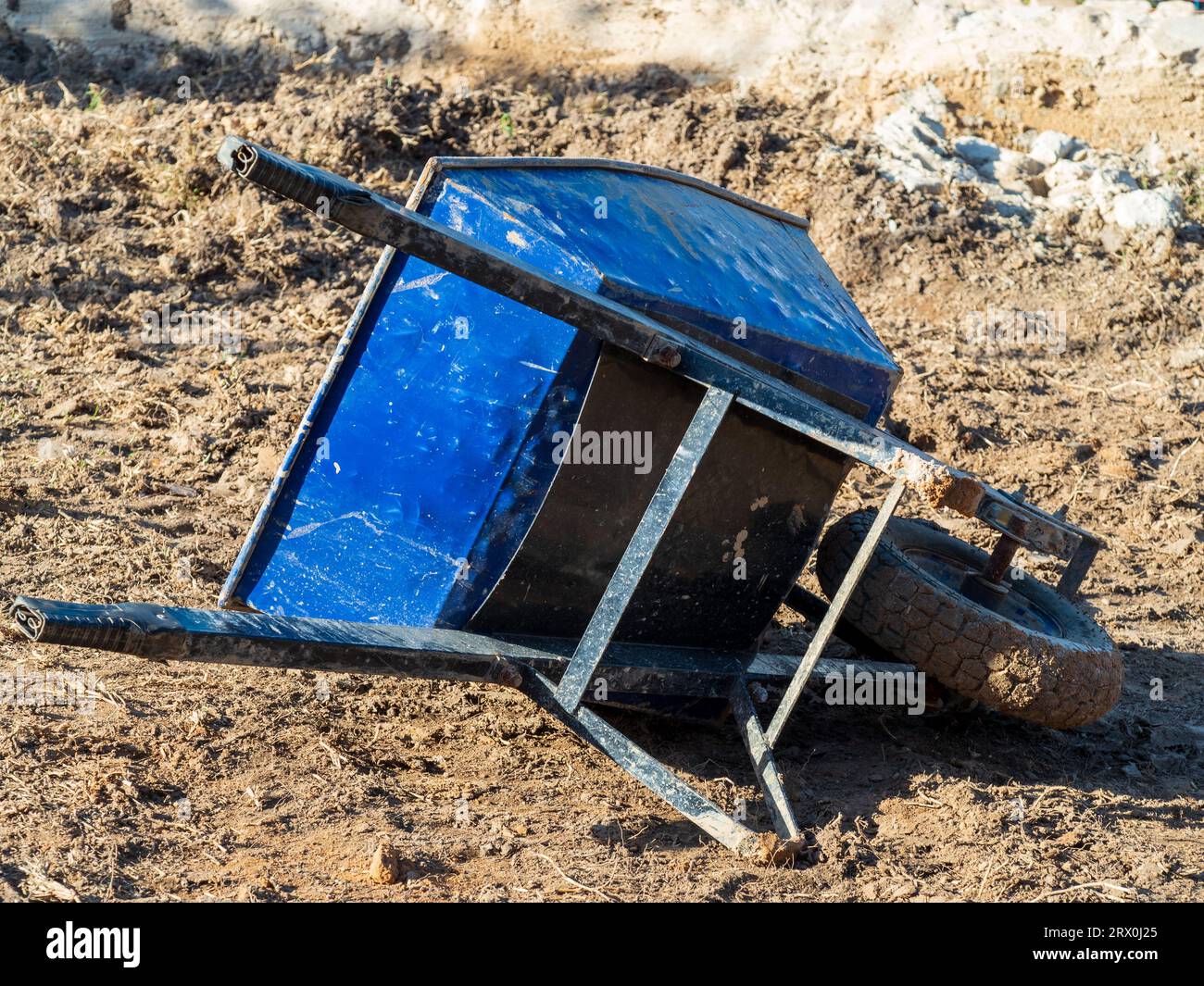A beaten up looking old wheelbarrow lies abounded in a backyard under ...