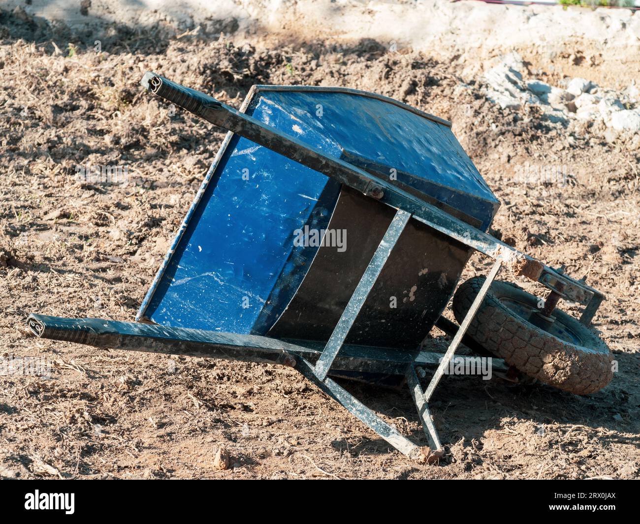 A beaten up looking old wheelbarrow lies abounded in a backyard under ...