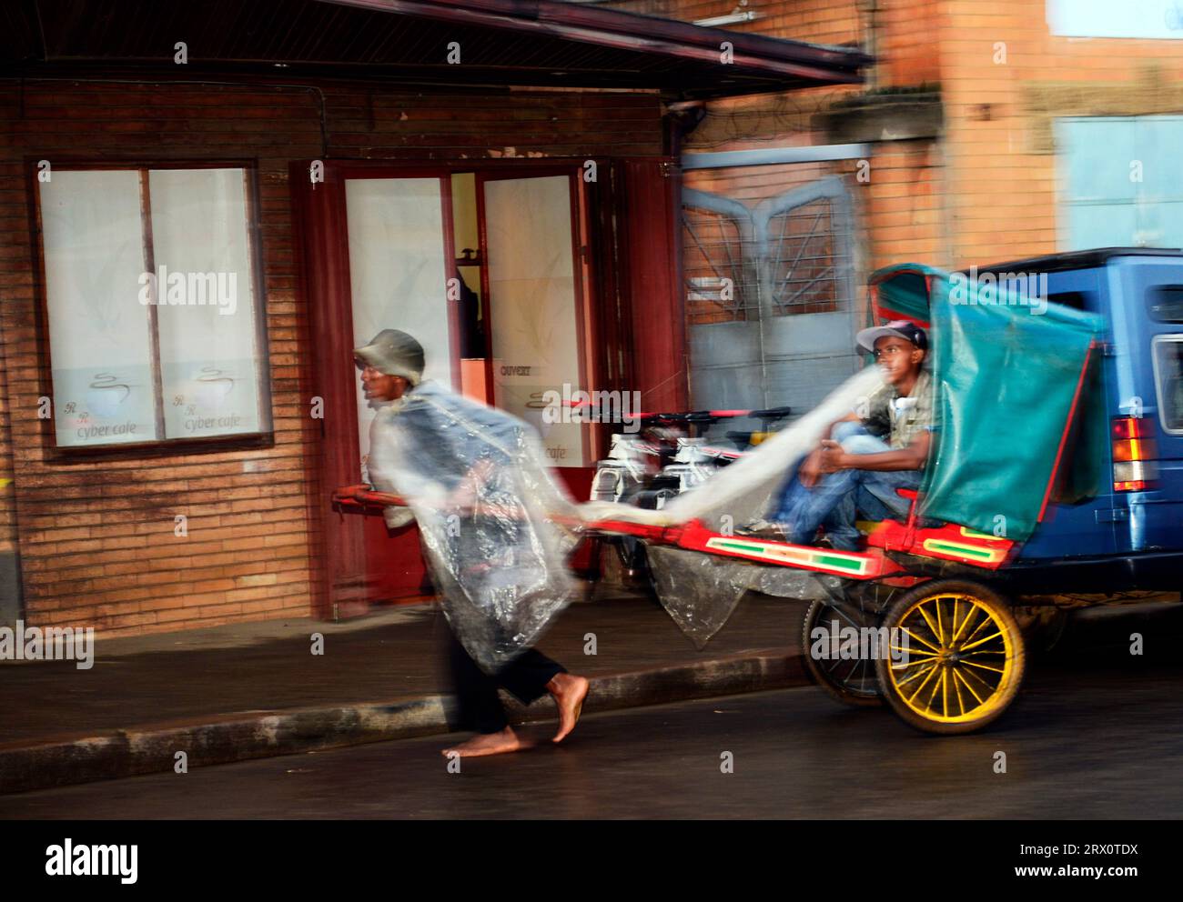 A Malagasy man pulling his pousse pousse on a rainy day Stock Photo - Alamy