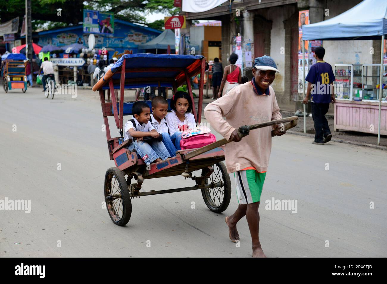 Malagasy primary school children going to school in a pousse pousse in ...