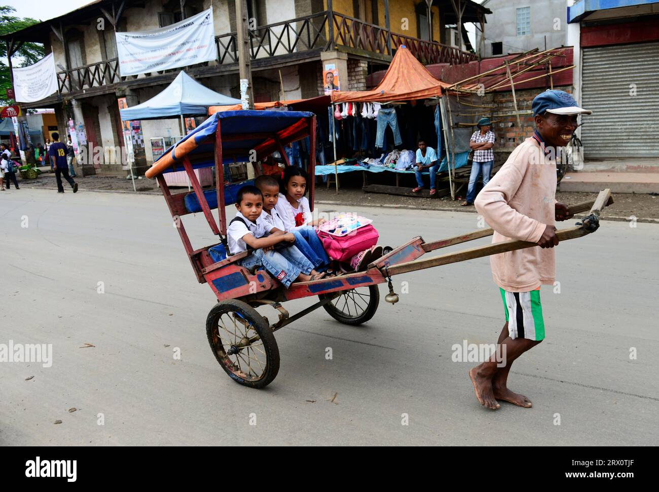Malagasy primary school children going to school in a pousse pousse in ...