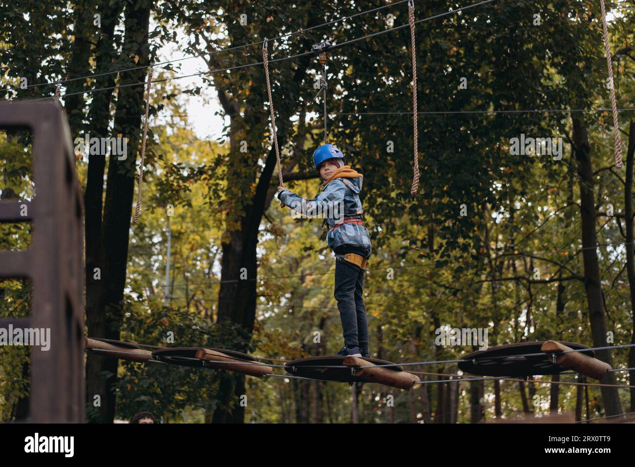 teenage boyin outdoor adventure park passing obstacle course. high rope ...