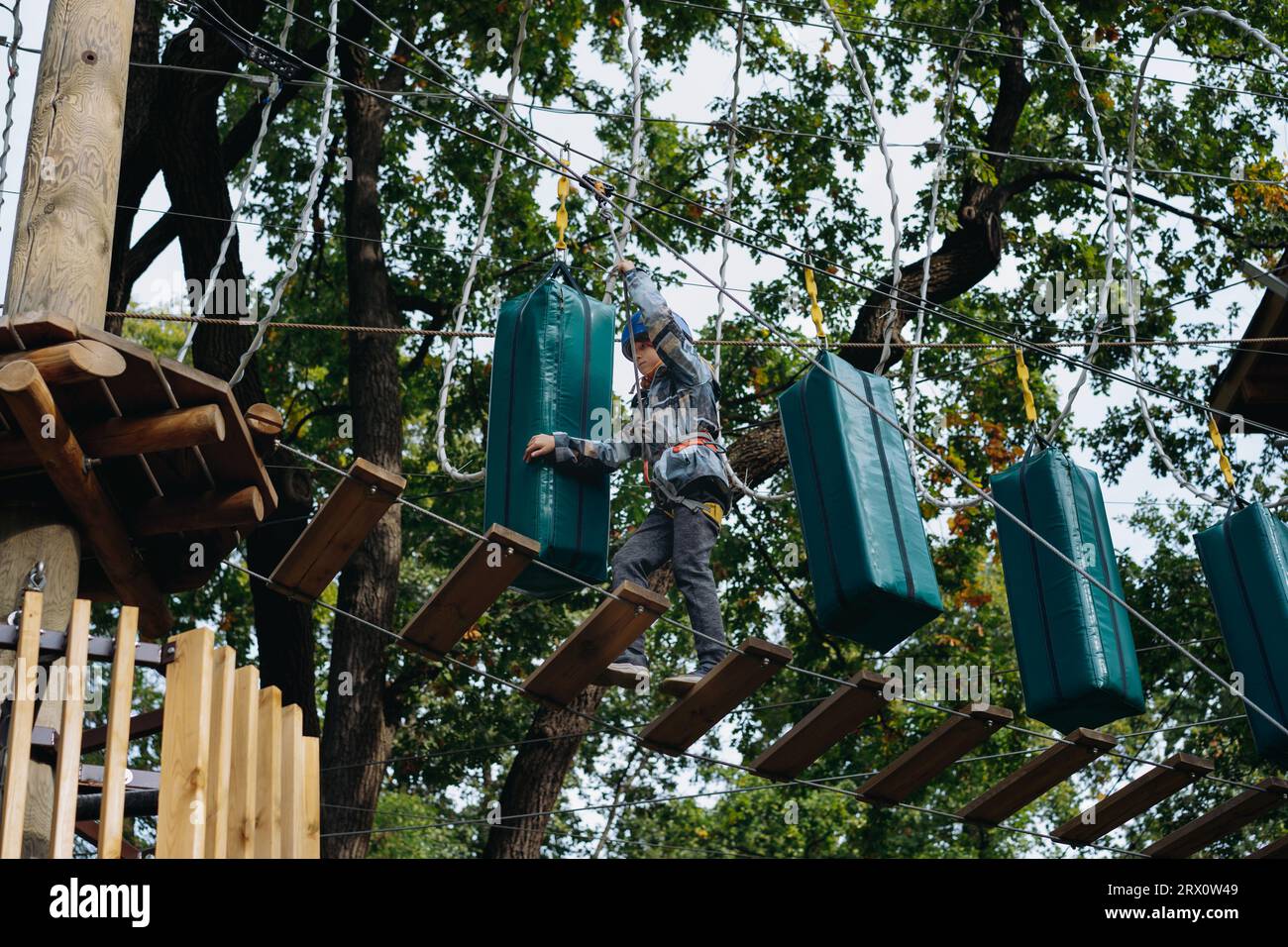 teenage boyin outdoor adventure park passing obstacle course. high rope ...