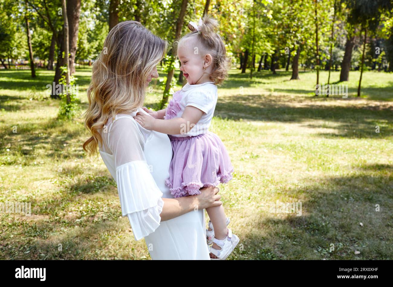 Mother and daughter walk in the summer city park. Childhood, leisure and people concept - happy ...