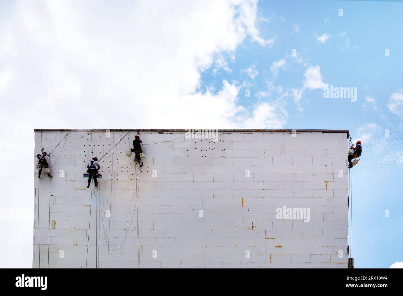 Workers insulate the building wall. High-rise works. Industrial ...