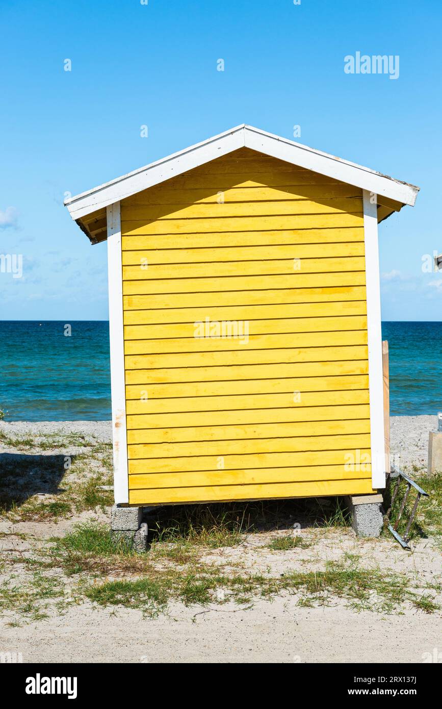 Frontal view of the back of a yellow wooden bathing hut on the beach of ...