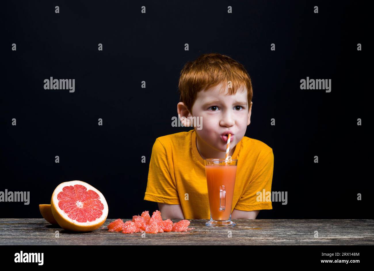 the boy drinks bitter and sour juice from red grapefruit, the juice is ...