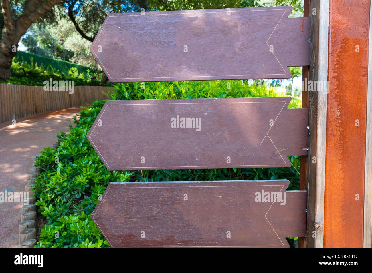Three blank directional signs pointing to the left in a park or forest ...