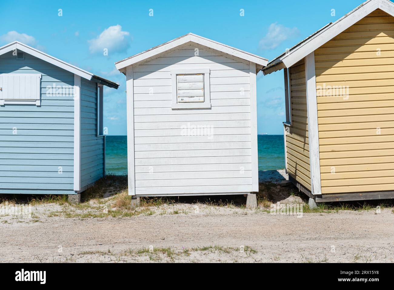 Colourful, windswept wooden bathing huts in the sand dunes on the beach ...