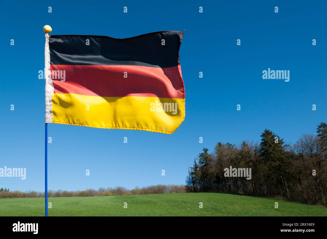 A vibrant, sunlit image of the German national flag, waving in the wind ...