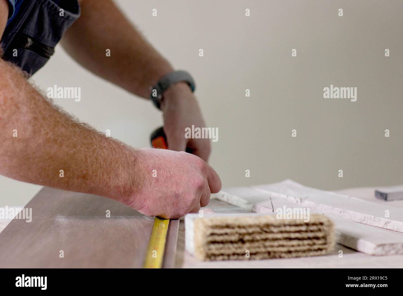 Professional tiler measuring and sticking with tape for cutting ceramic ...