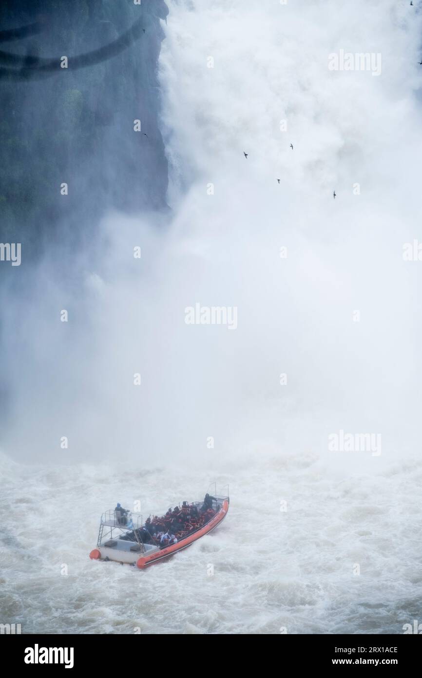 Iguazú waterfalls, boat with tourists in front of a powerful water ...