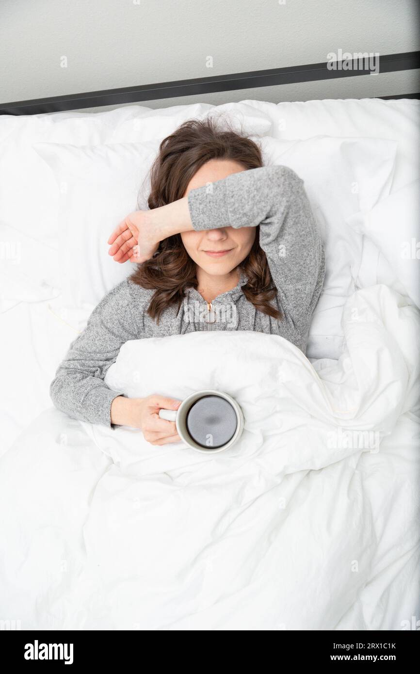 A tired woman drinking coffee in bed Stock Photo - Alamy