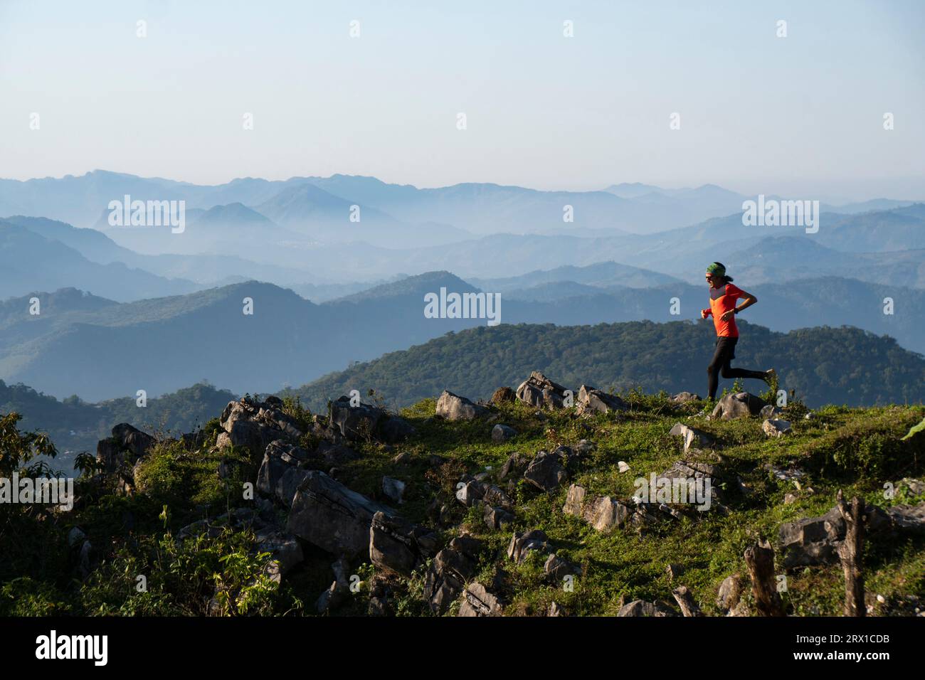 One man running on a hill with mountain layers in the background Stock ...