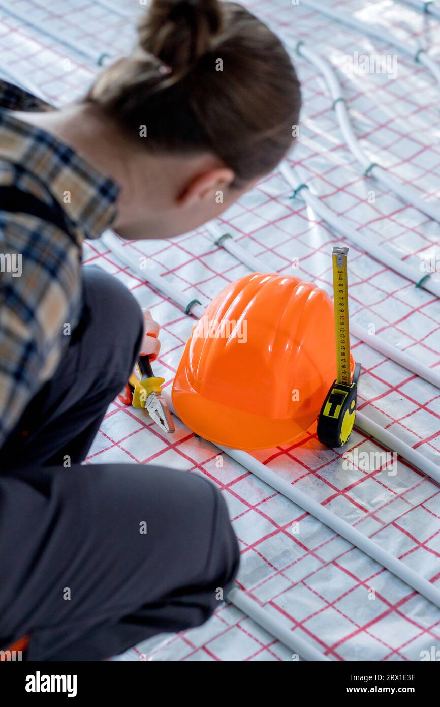 Worker near tools for repair hard hat, plier, glove on warm floor ...
