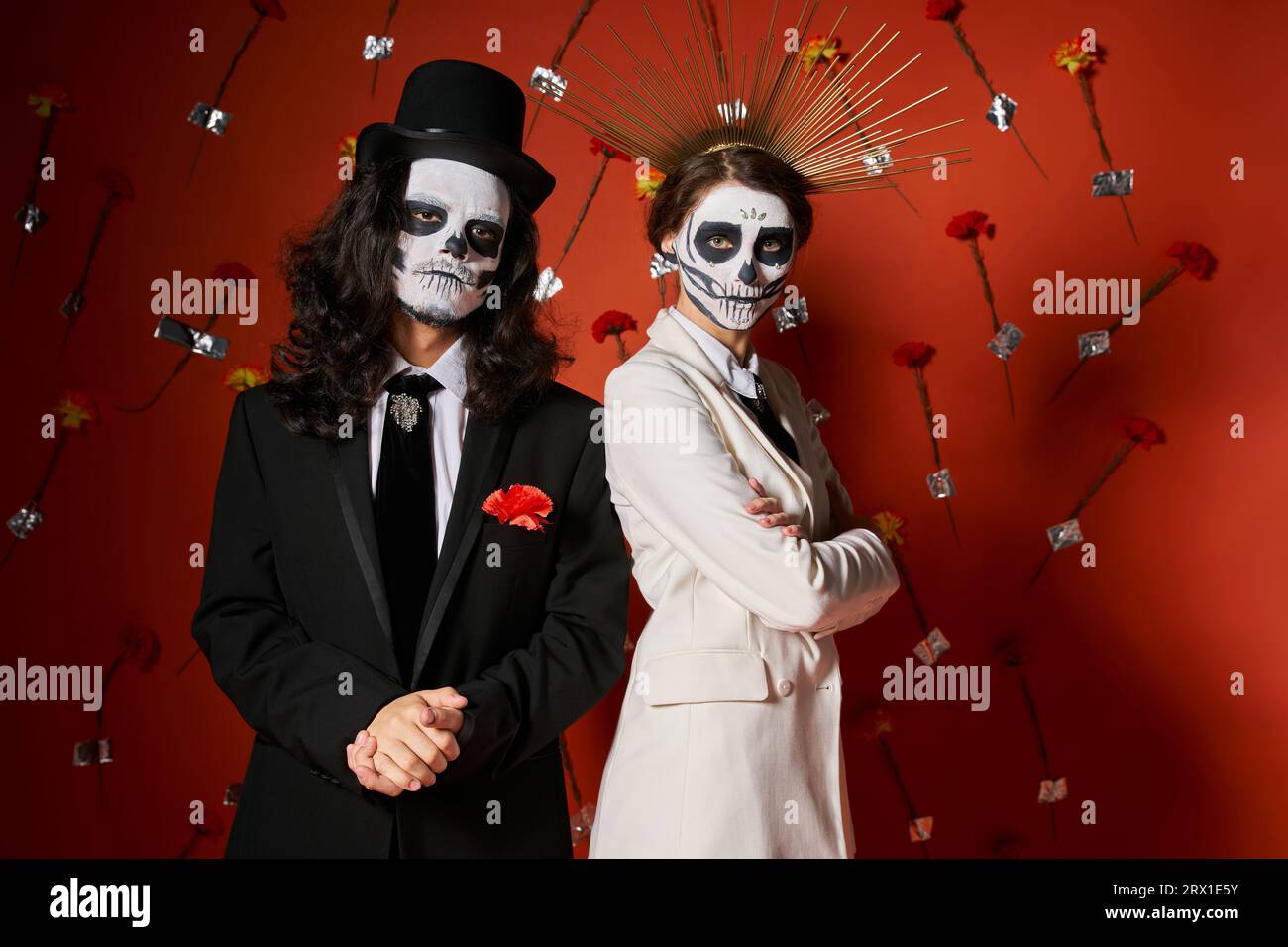 woman in crown and skull makeup with folded arms near spooky man in top ...