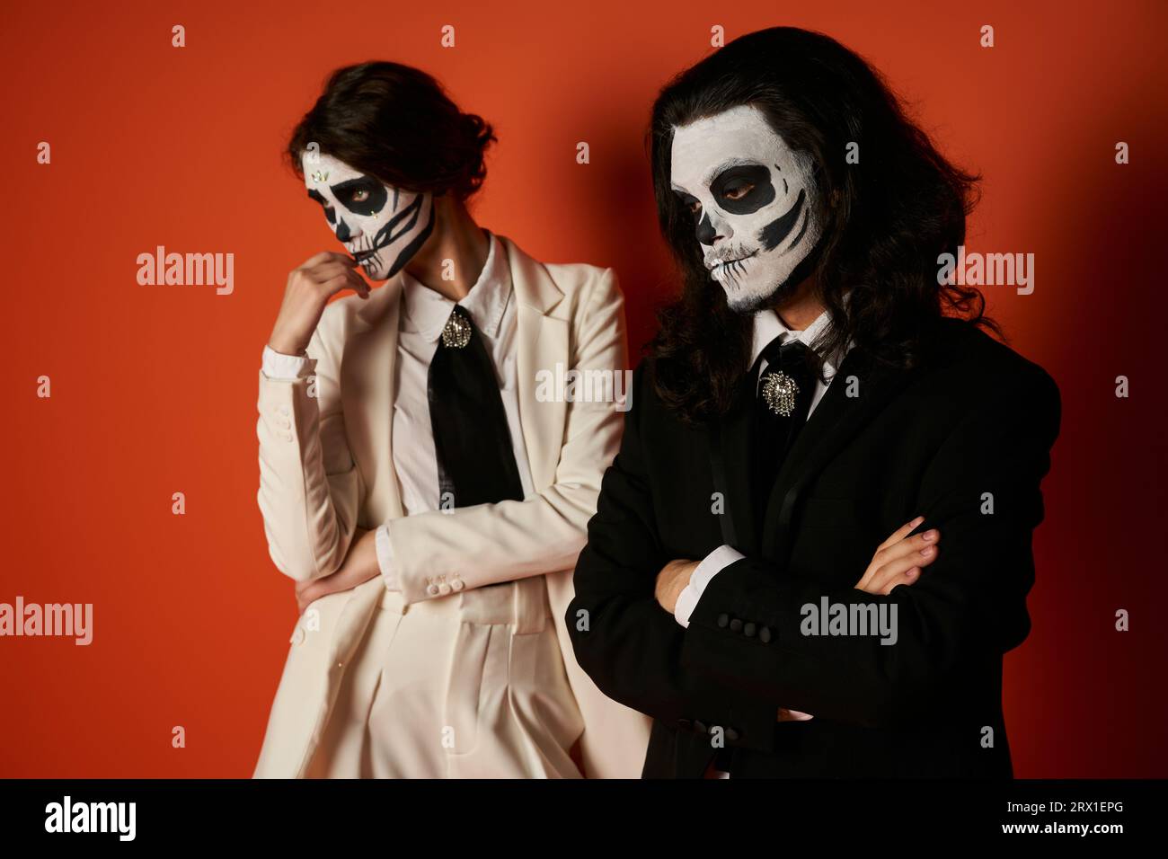 thoughtful couple in sugar skull makeup and elegant suits looking away ...