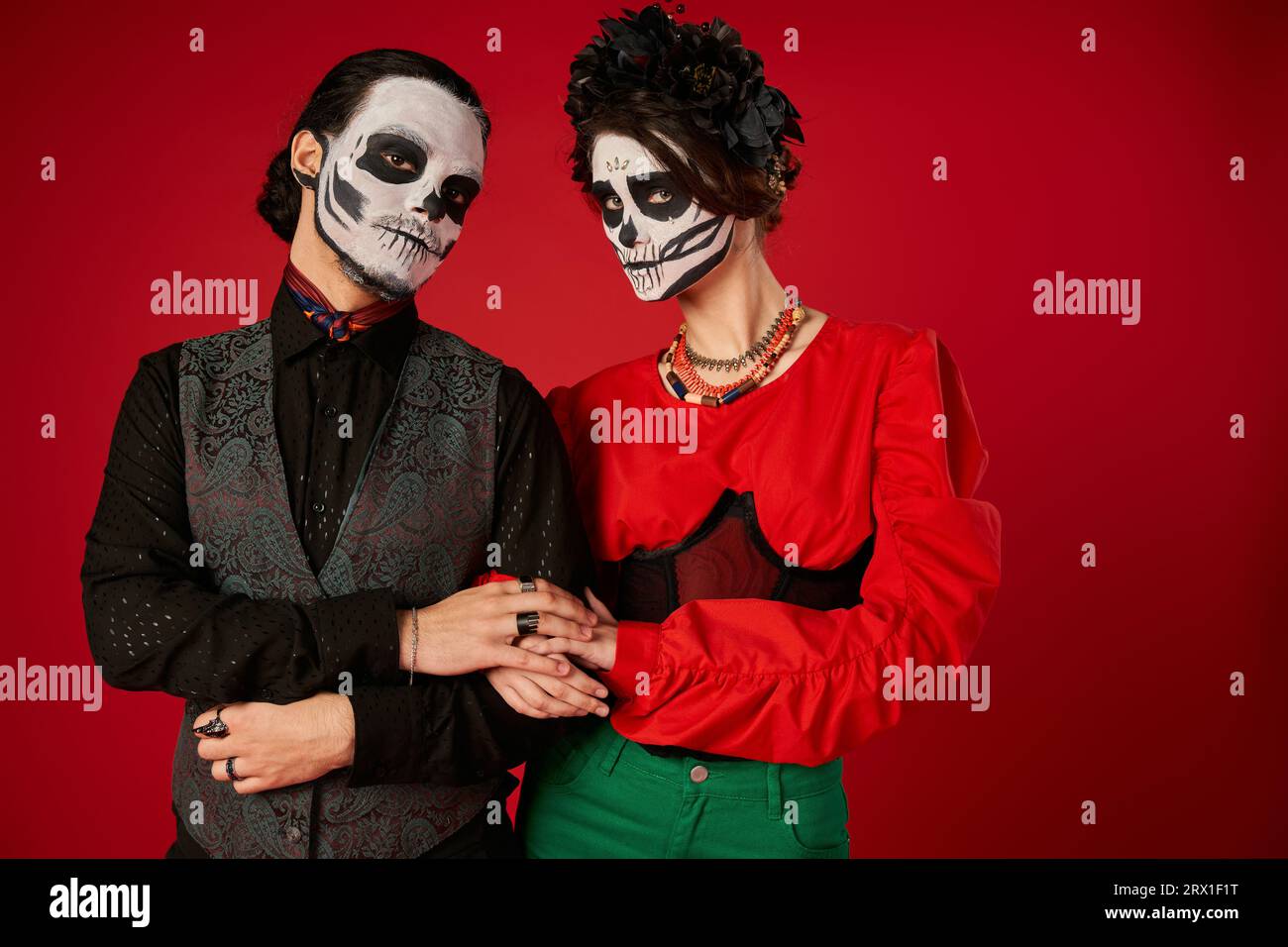 couple in skull makeup touching hands of each other and looking at ...