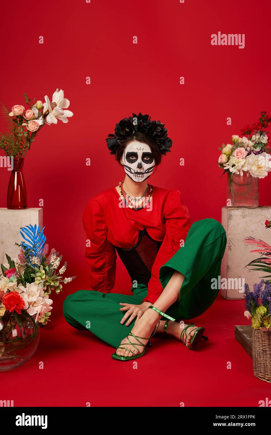 woman in catrina makeup sitting near traditional dia de los muertos ...