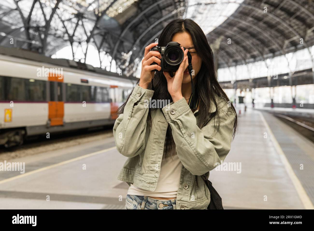Female photographer taking a picture with a camera in a train station ...