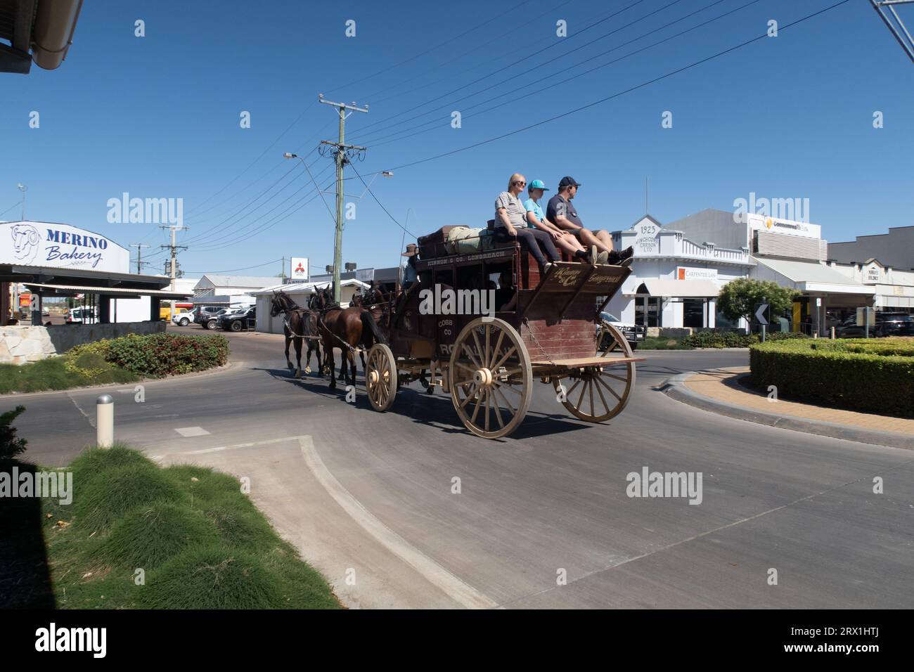 an old Cobb and Co stage coach lead by horses travel down main street ...