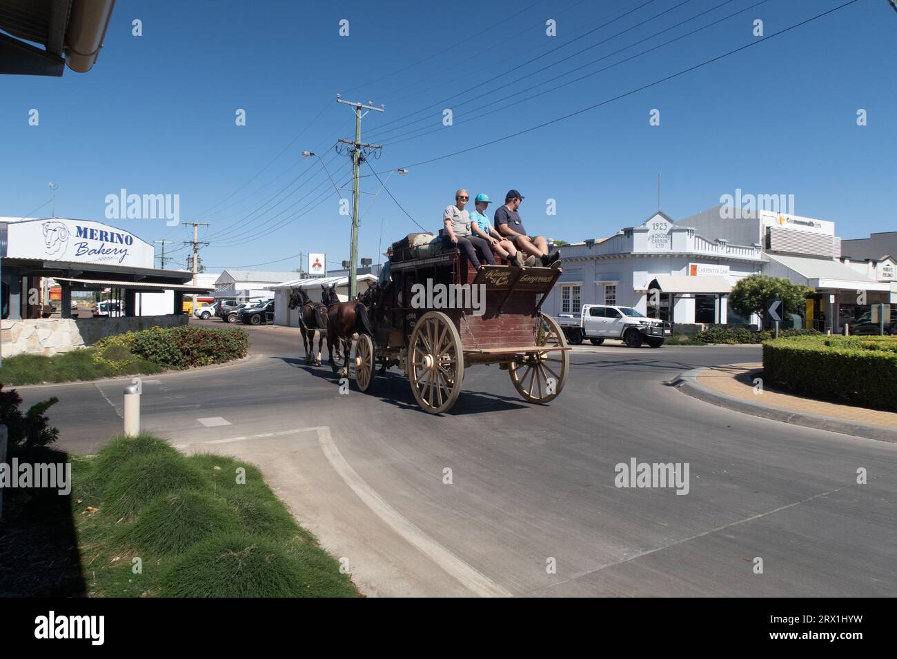an old Cobb and Co stage coach lead by horses travel down main street ...