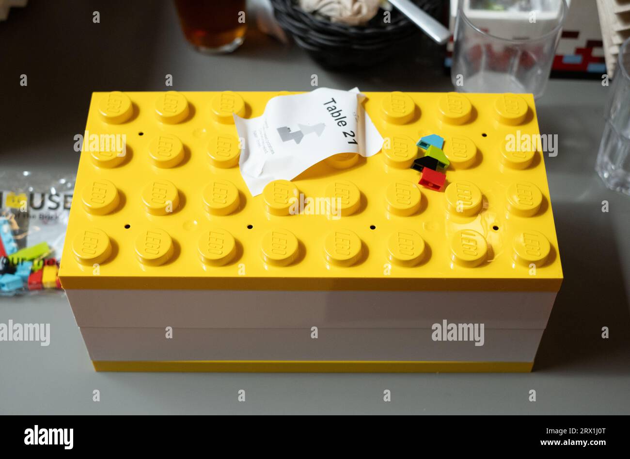 Photograph of a giant yellow LEGO brick on a dining table, with a ...