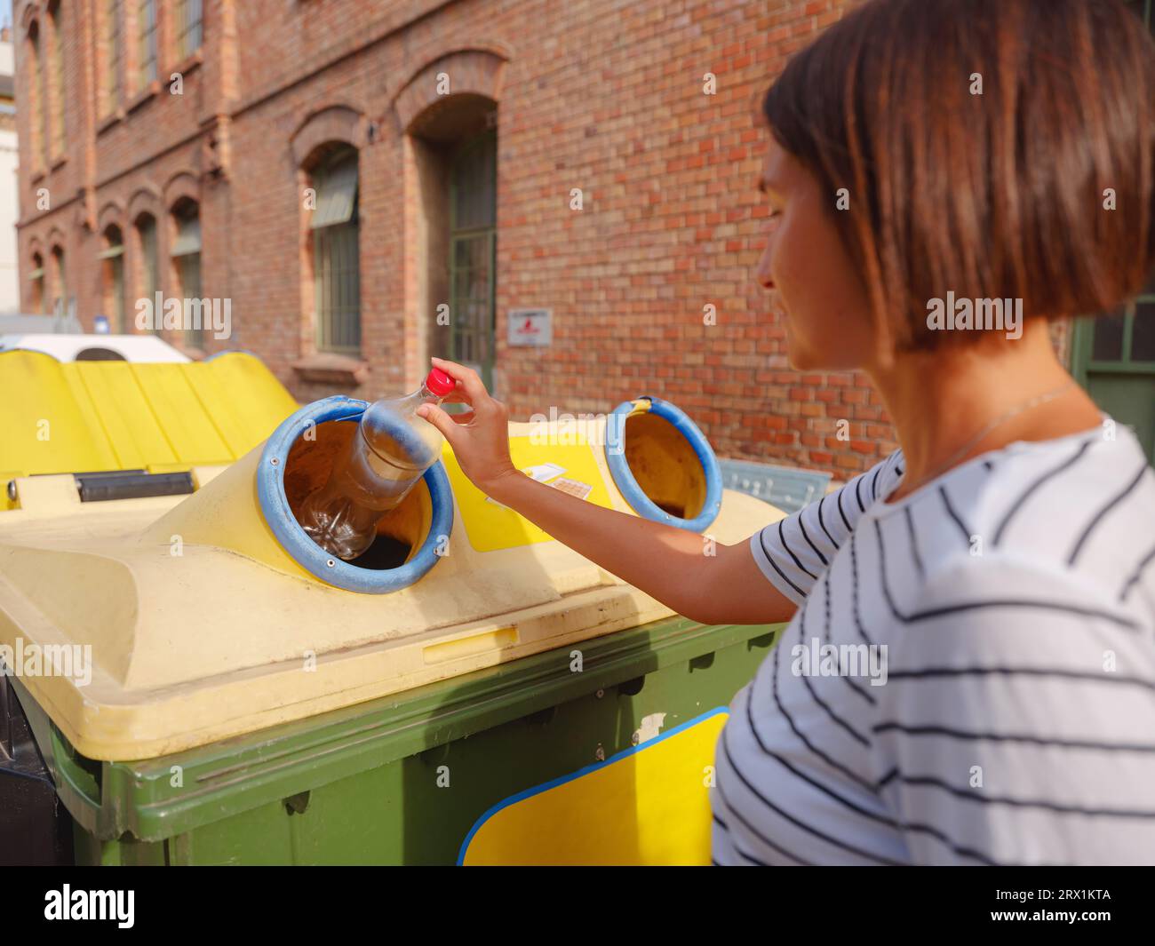 woman throwing plastic bottle Recycling bin stand on european street ...