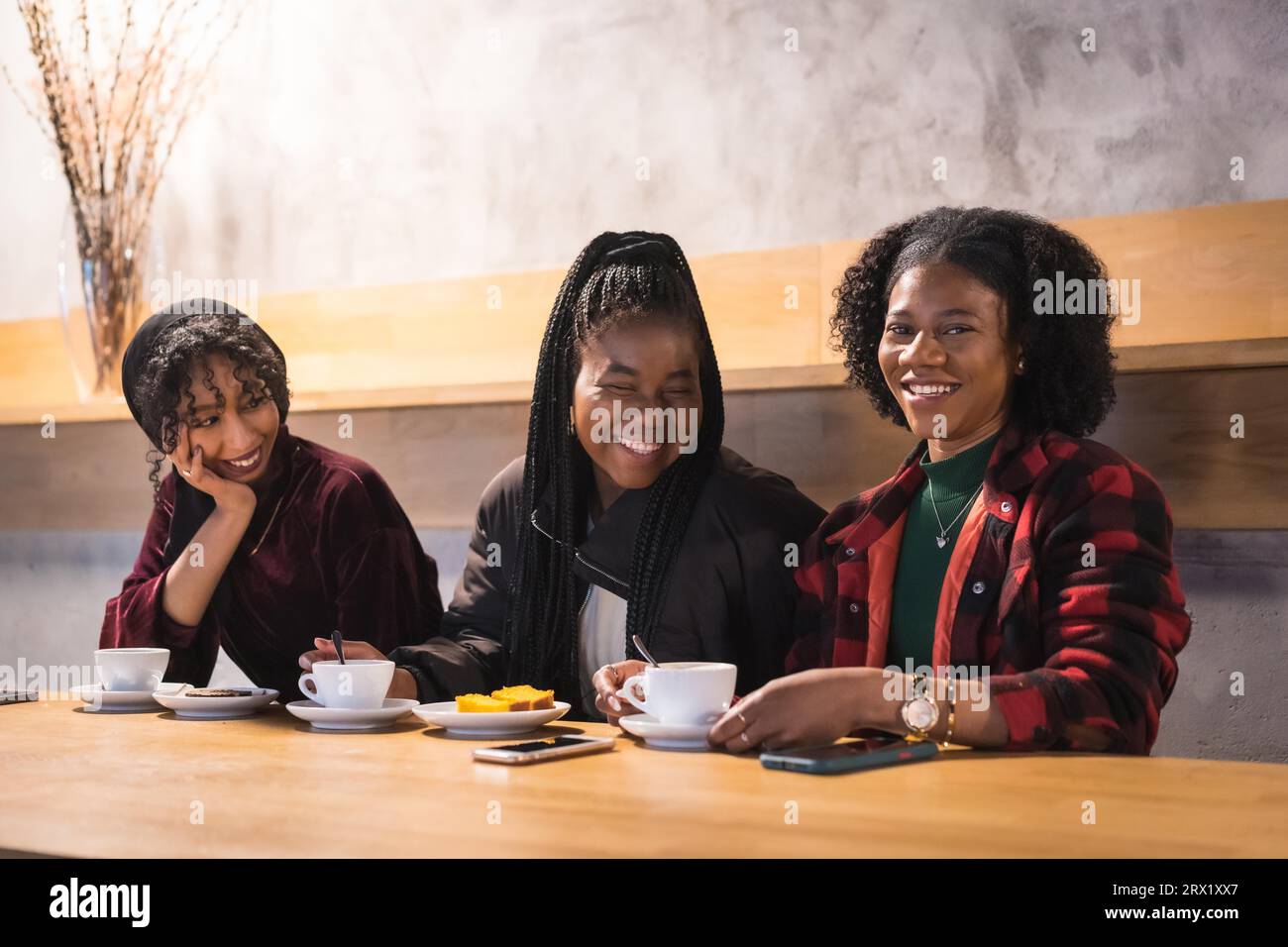Portrait of three cheerful multicultural friends drinking coffee in a ...
