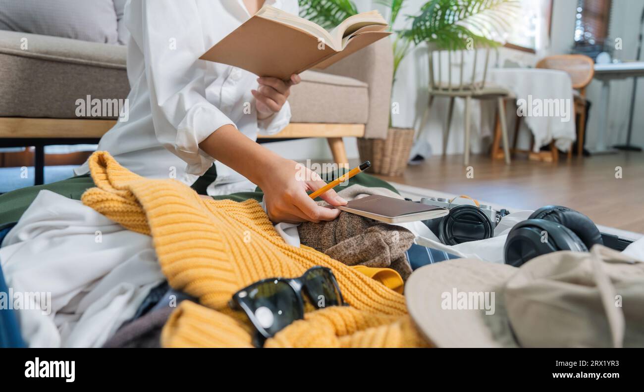 Making check list of thing to pack for travel. Woman writing paper take ...