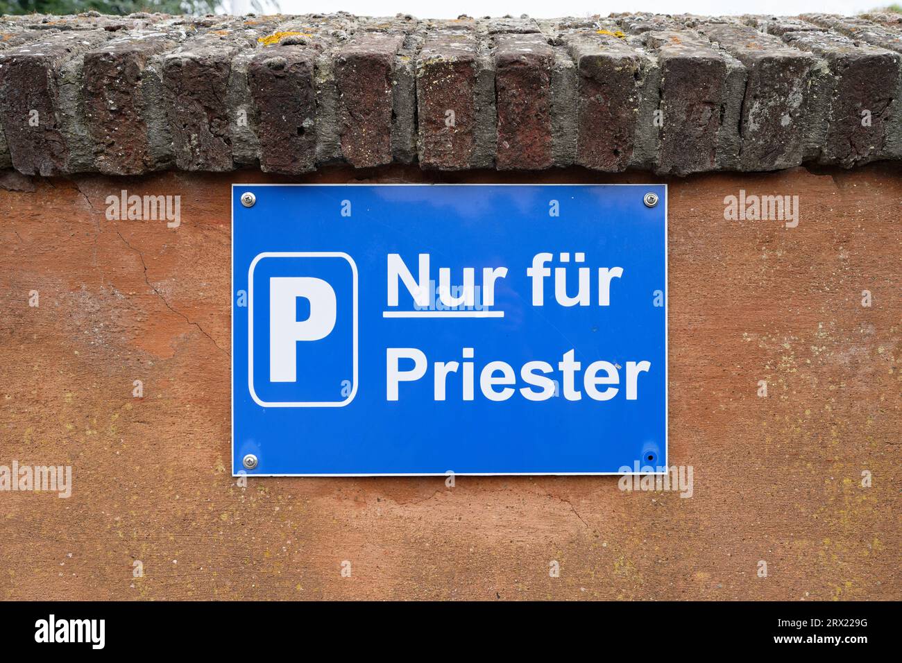 blue and white sign Parking for Priests only on a stone wall Stock ...