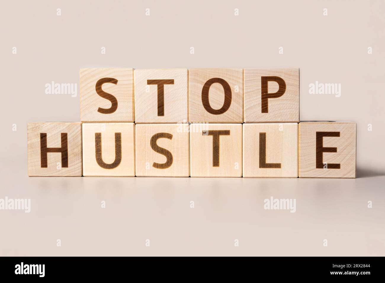 The word STOP HUSTLE on cubes on a beige studio background. Copy Space ...