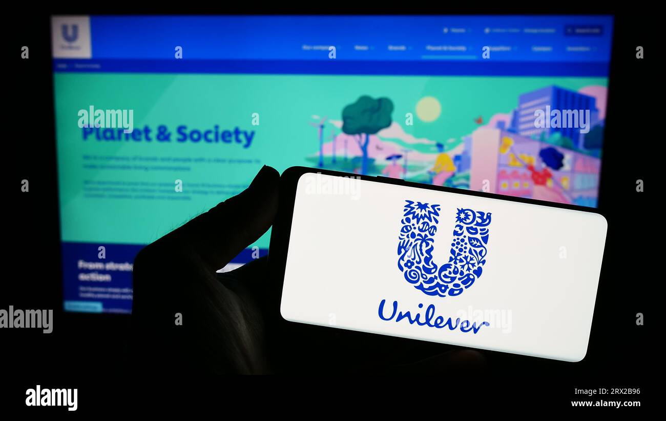 Person holding mobile phone with logo of British consumer goods company ...