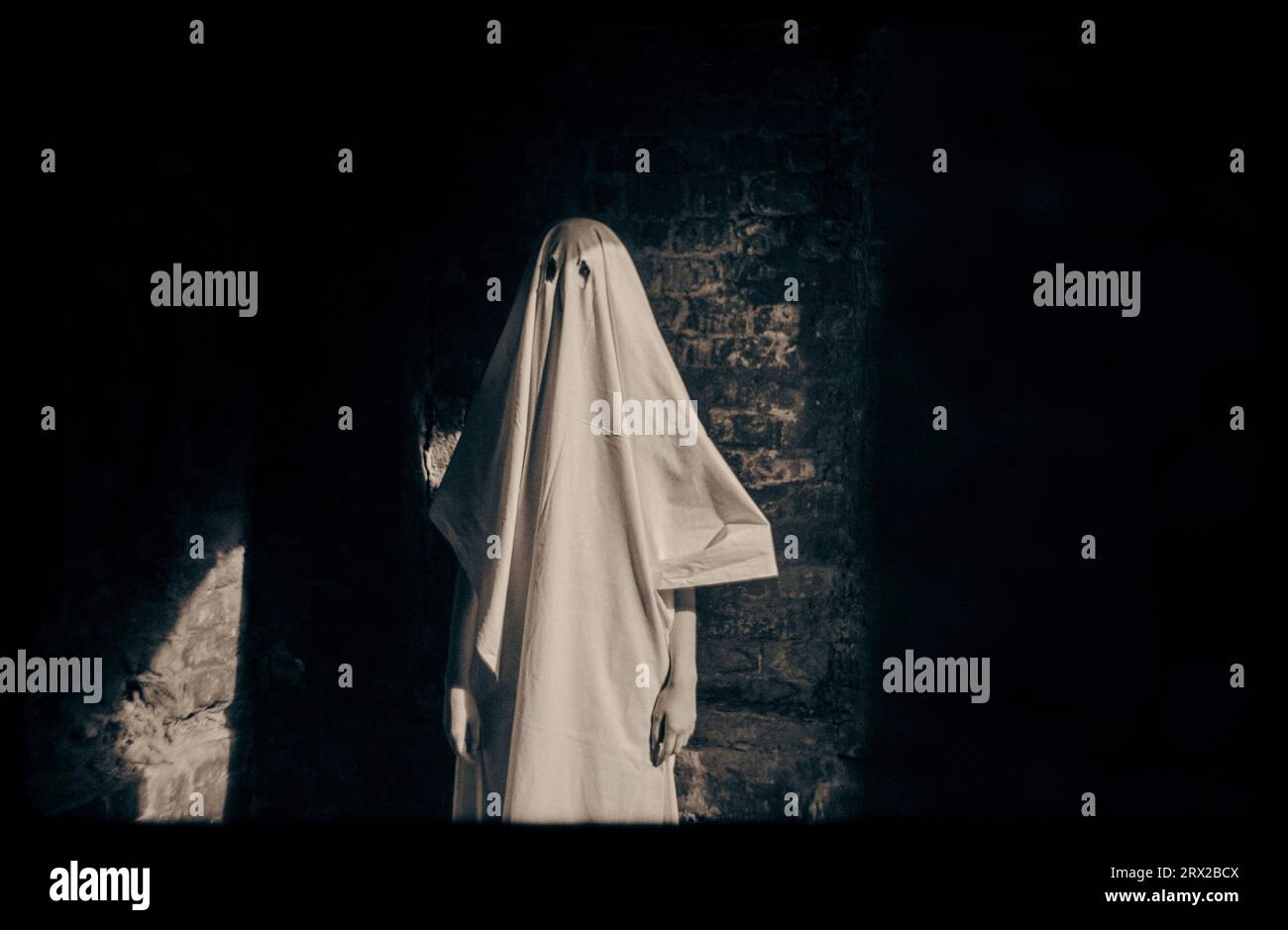 A spooky ghost stands in an abandoned old building at night. The eerie ...