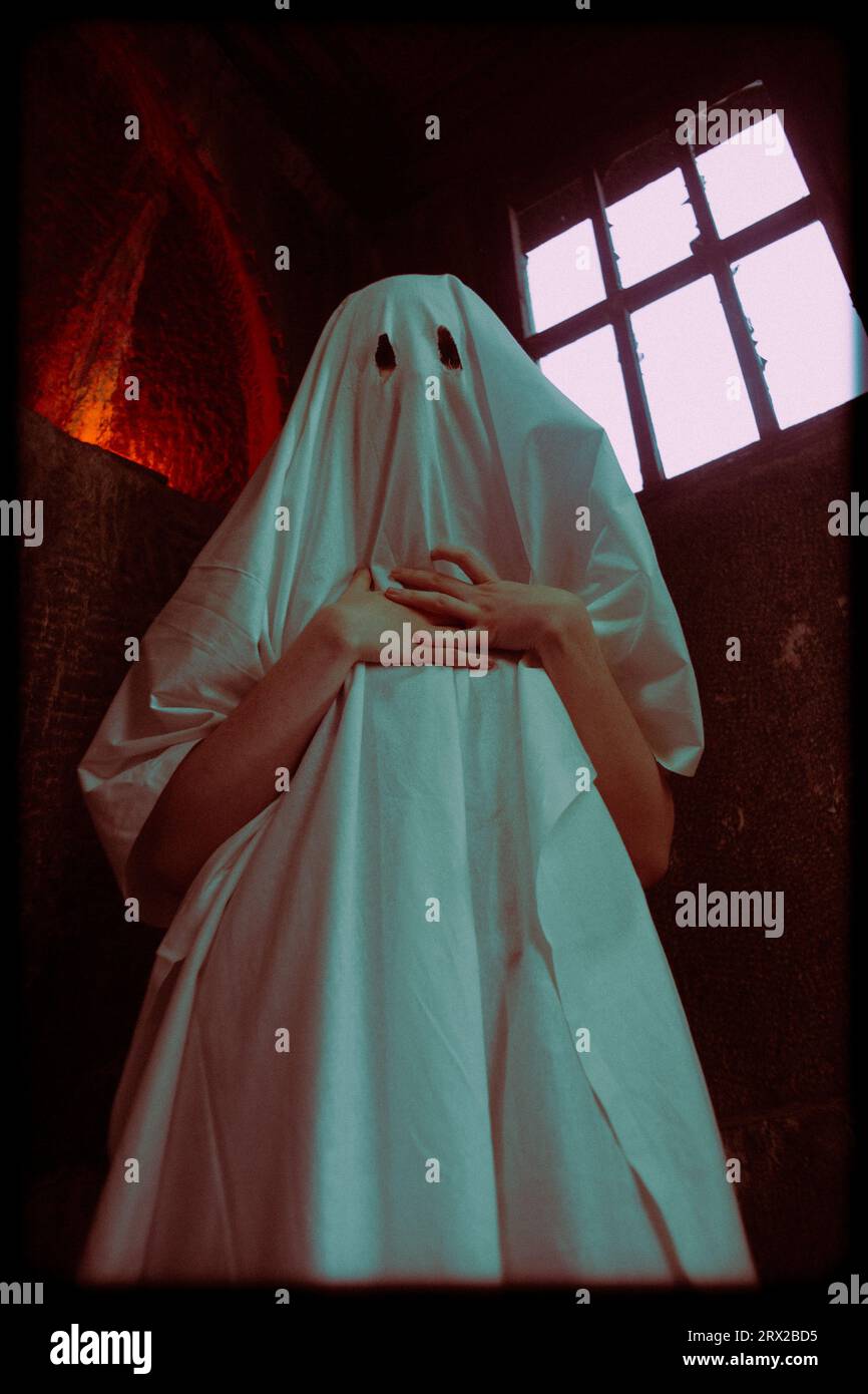 A spooky ghost standing in a crypt illuminated by an otherworldly red ...