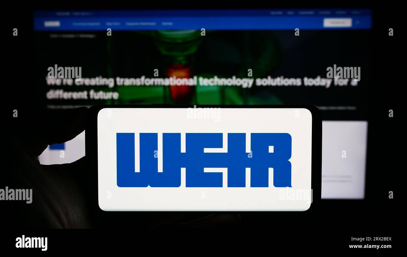 Person holding cellphone with logo of British company The Weir Group ...
