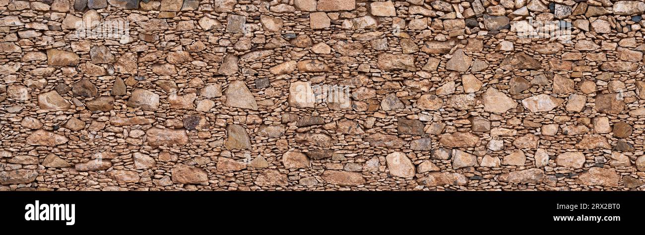 Brown panoramic natural stone wall with pattern of big and small stones ...