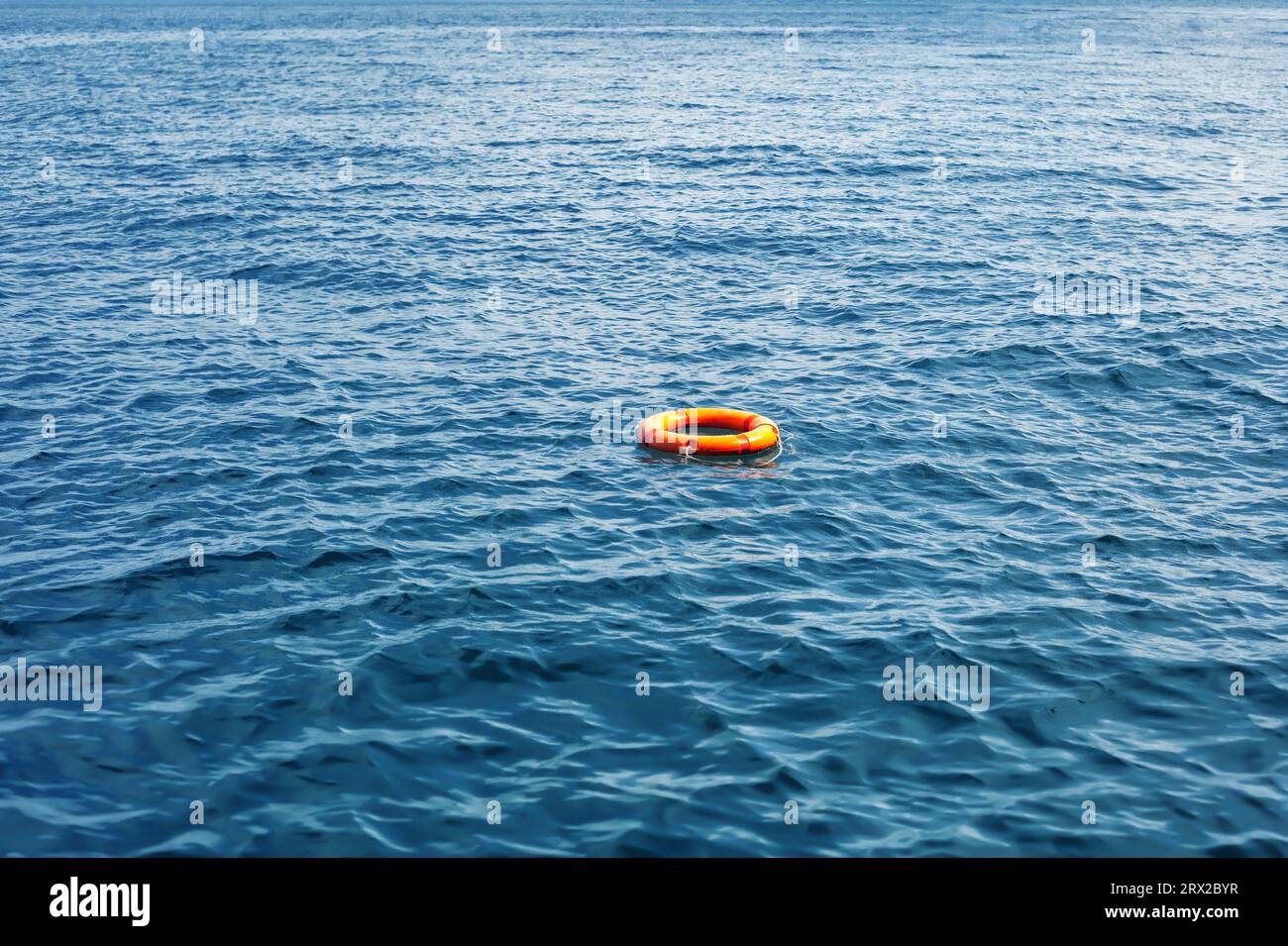 Orange life buoy float in vast expanse of blue sea. Red lifebuoy drift ...